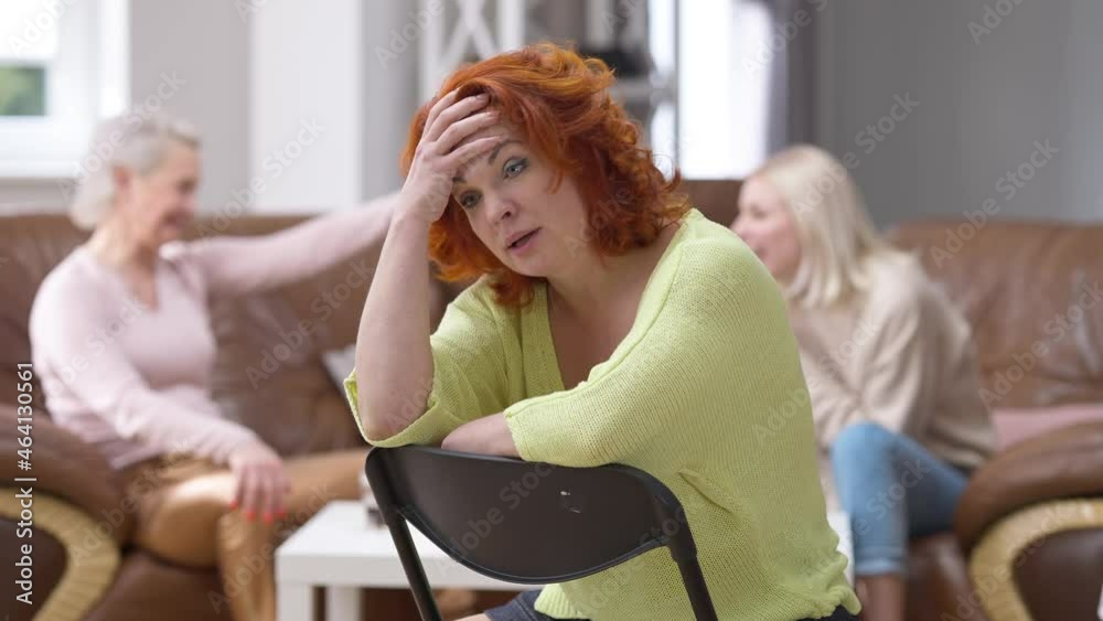Displeased redhead woman sitting on chair shaking head talking as ...