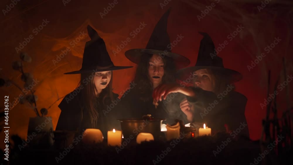 In a room shrouded in cobwebs, three young witches are sitting near a ...