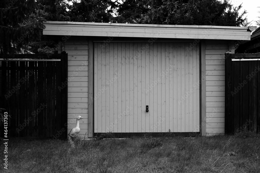 Garage in einem ungepflegten Garten mit kitschiger Figur einer Gans in ...