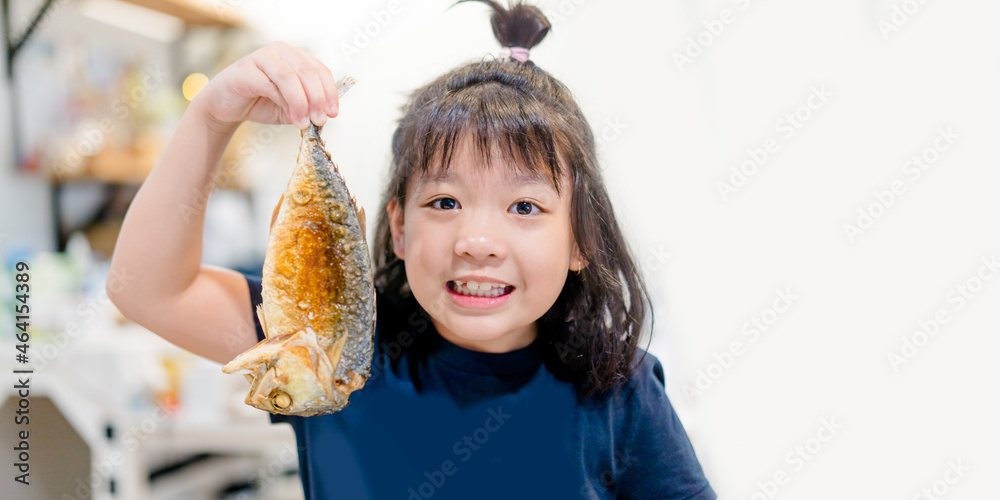 Portrait kid girl having homemade deep fried fish mackerel at home, A ...