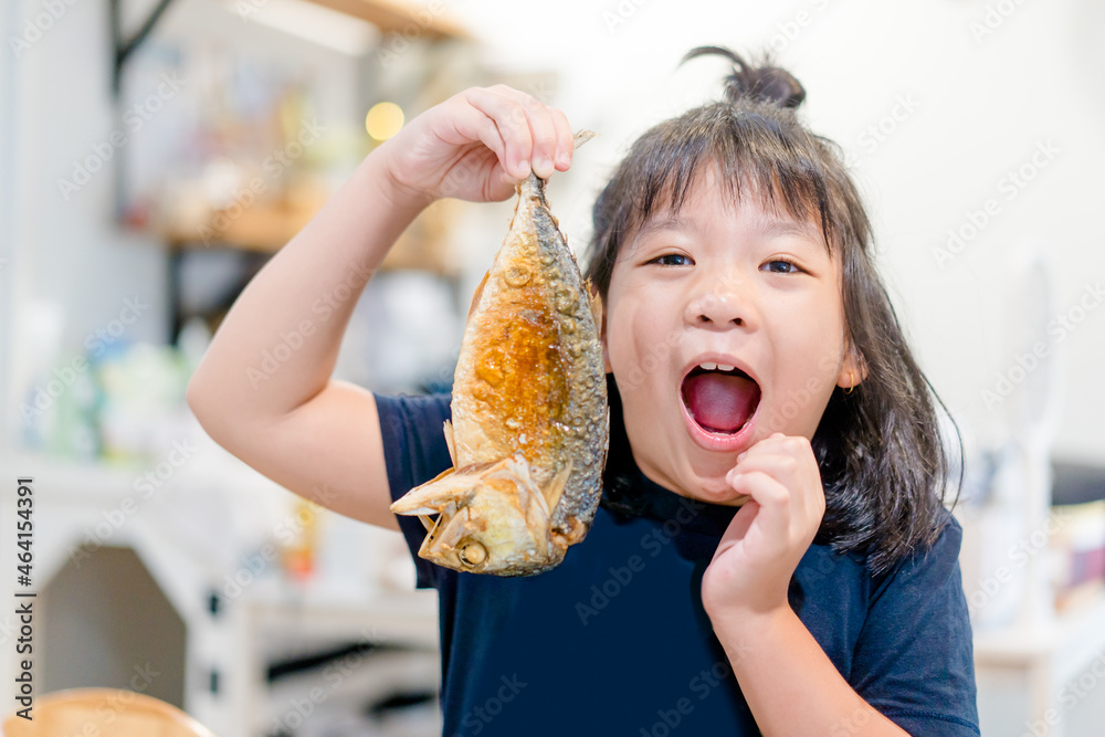 Portrait kid girl having homemade deep fried fish mackerel at home, A ...