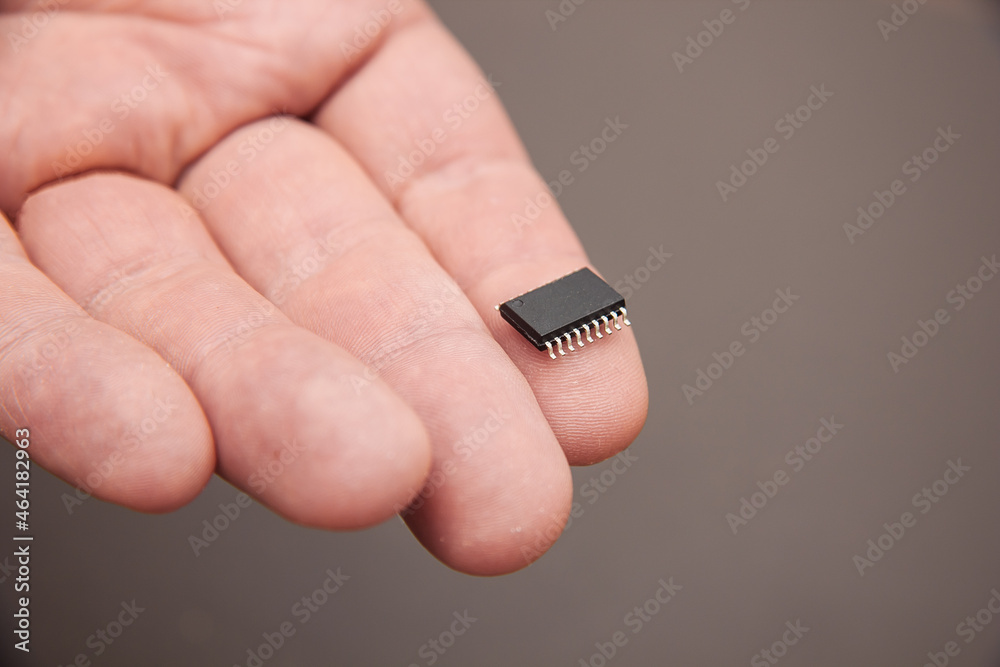 Hand holds chip compenent. Embedding the chip under human skin ...