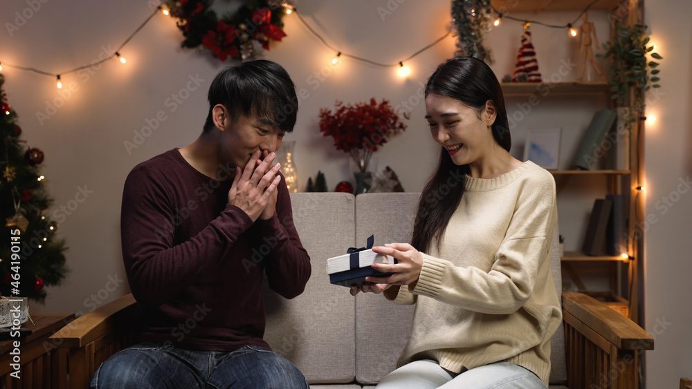 young couple in love celebrating xmas together in xmas eve at home. asian man surprised by ...