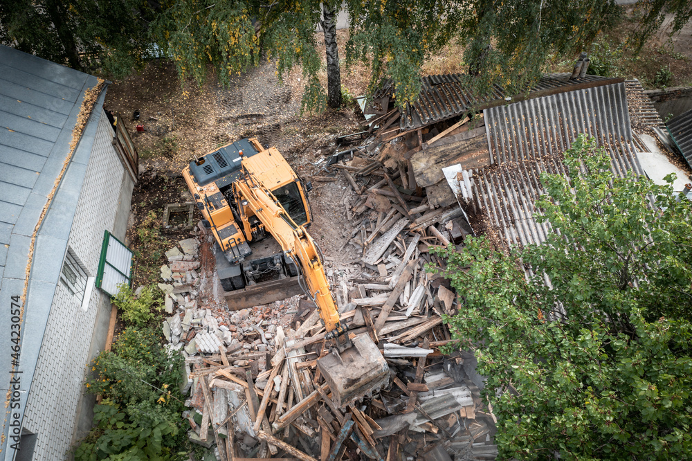 Demolition of building aerial view. Excavator breaks old house. Freeing ...