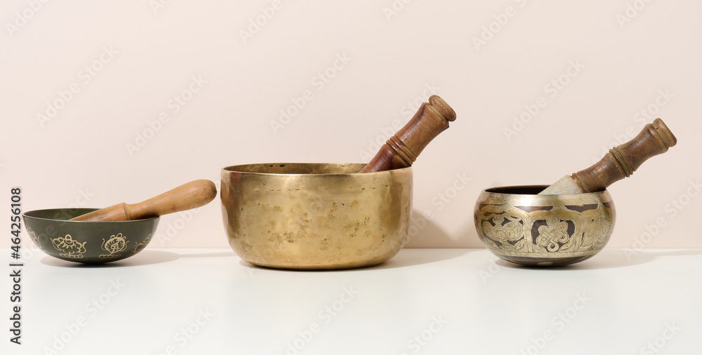 copper singing bowl and wooden clapper on a white table. Musical ...