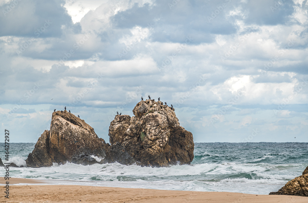 Beautiful sandy ocean beach with large rocks on shore and in water ...