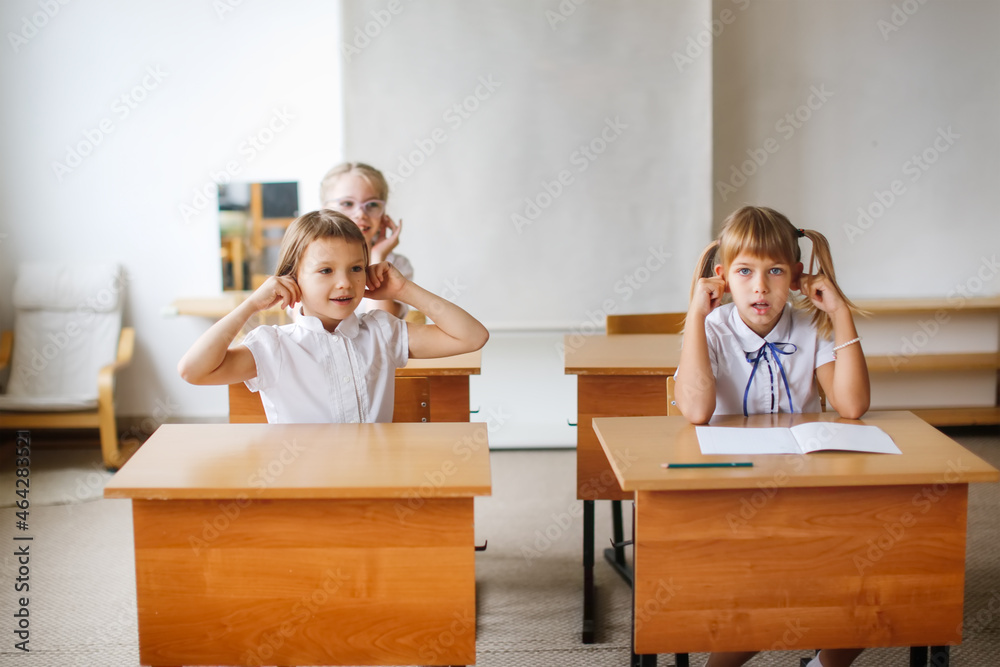 Children in class do exercises, kids pupils rub their ears and show ...