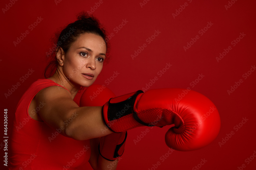 Boxer female athlete fights in red boxing gloves on a red background ...