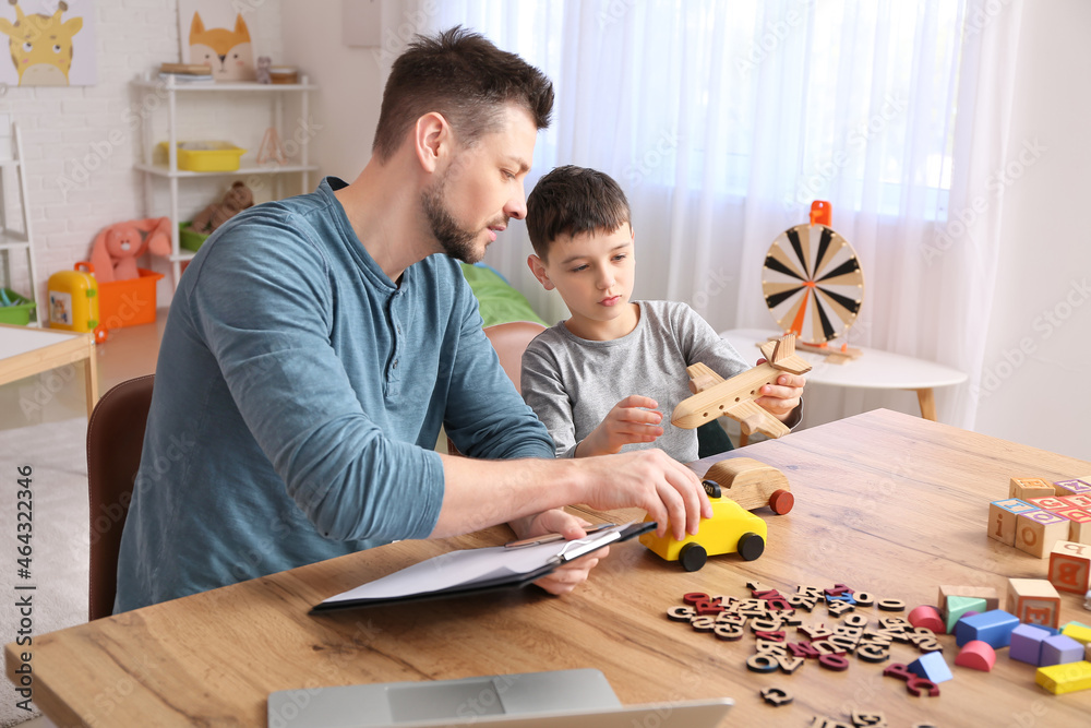 Male psychologist working with little boy in office. Autism concept ...