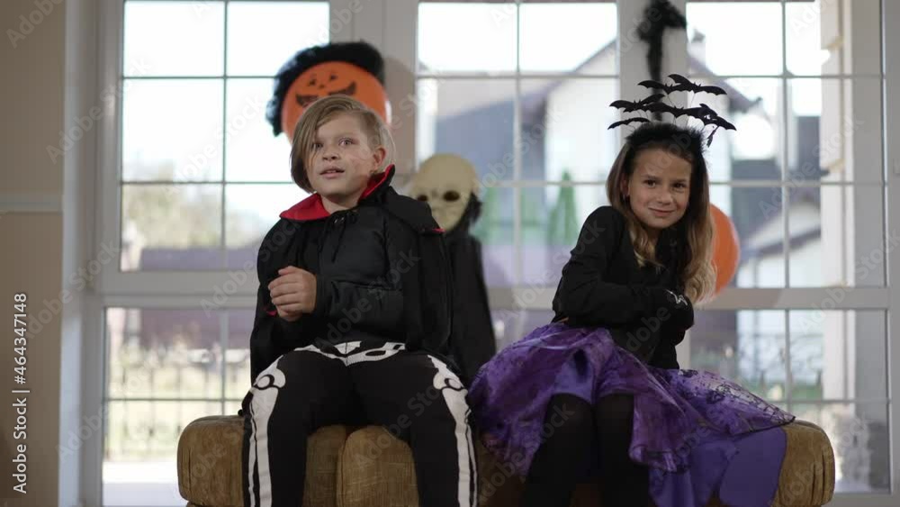 Front view two children watching horror movie indoors on Halloween ...