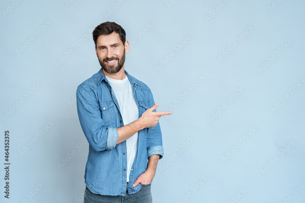 Smiling man freelancer pointing right with index finger and looking at ...