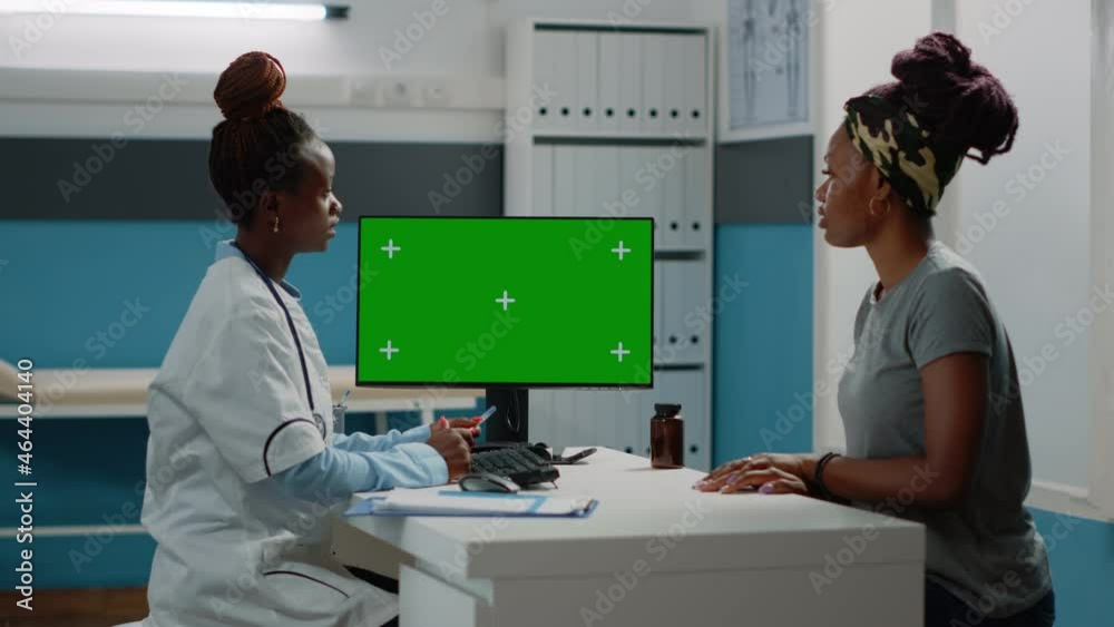Doctor and patient looking at computer with horizontal green screen in ...