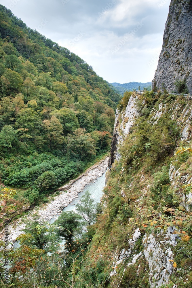 The mountain road goes into a gorge between a sheer cliff and a cliff ...