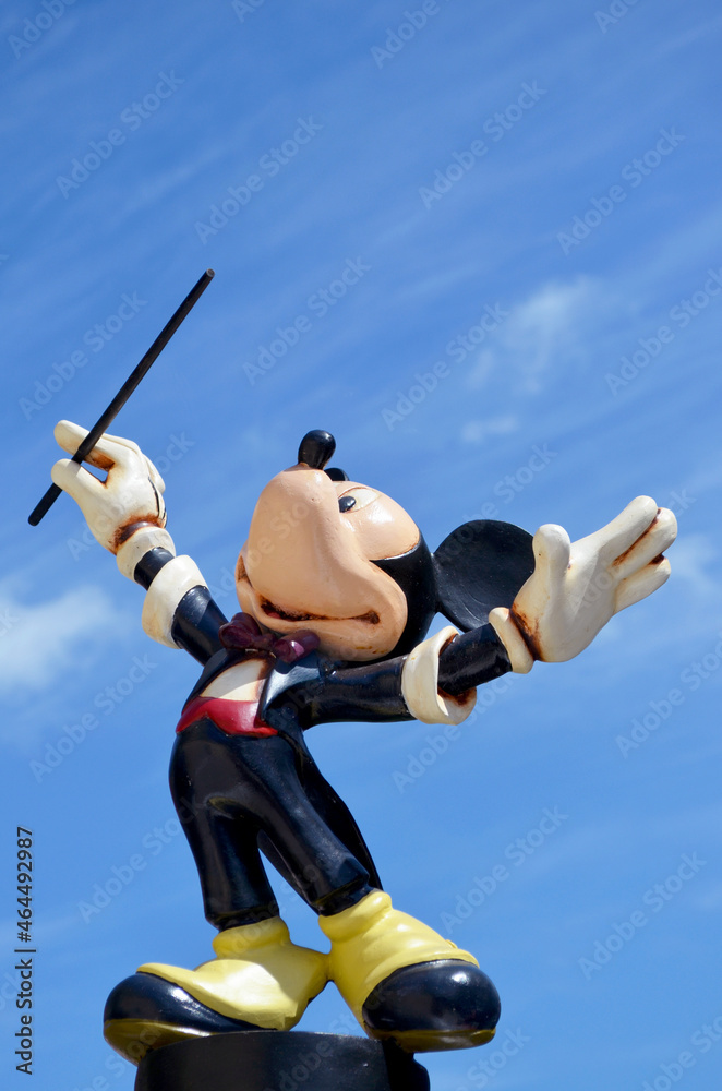 Studio image of Mickey Mouse figure Standing on a wall with a blue sky ...