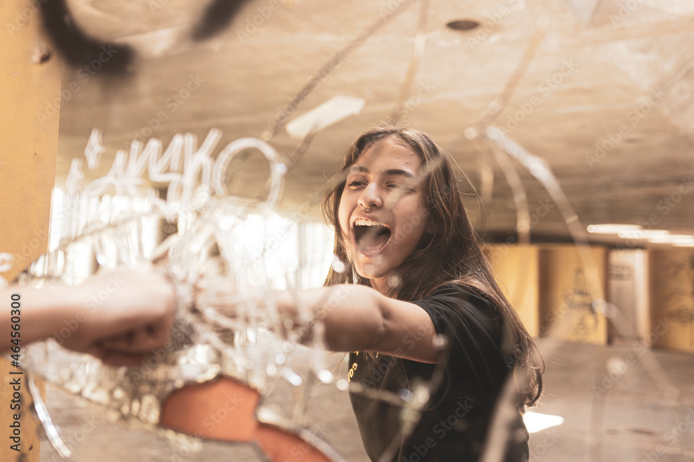 Young urban teenager girl punching and breaking a mirror in rage and ...