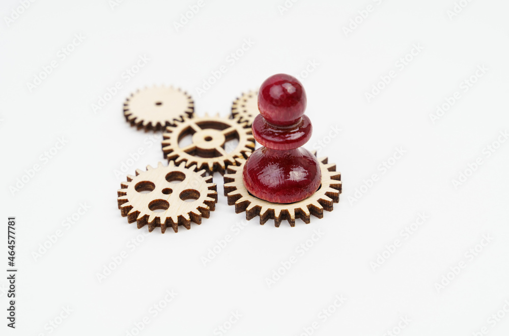 On a white background, there are wooden gears on which a pawn stands ...