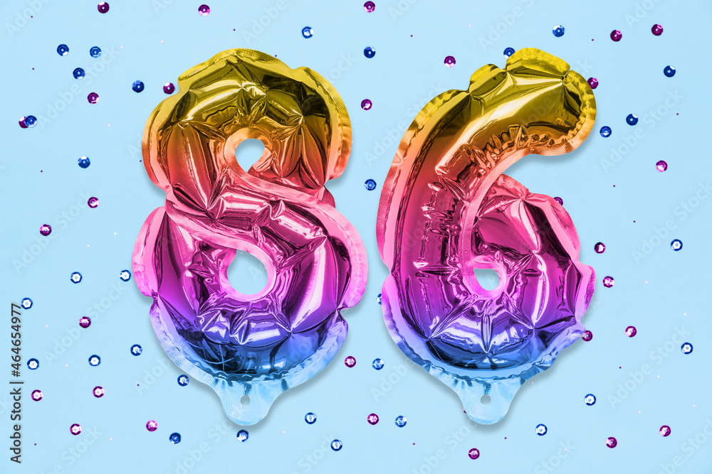 Rainbow foil balloon number, digit eighty six on a blue background with ...
