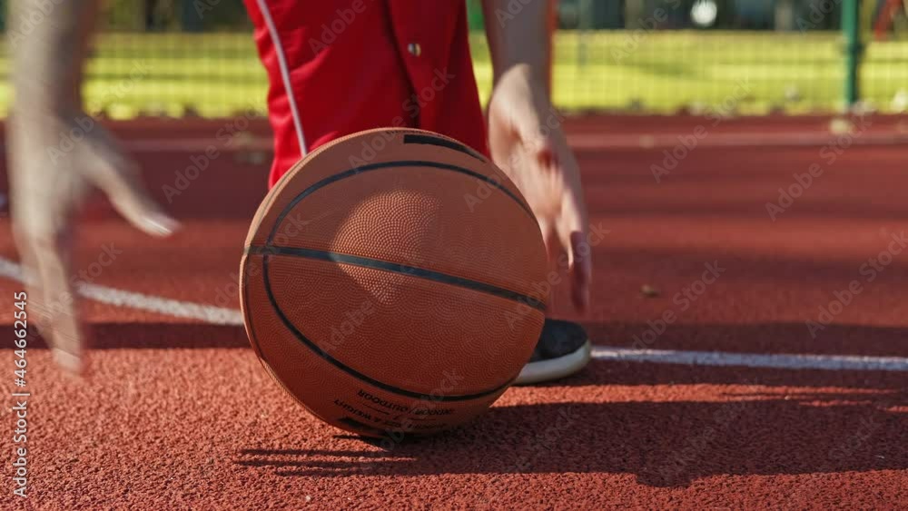 Ball on ground of basketball court. Basketball player taking ball from ...