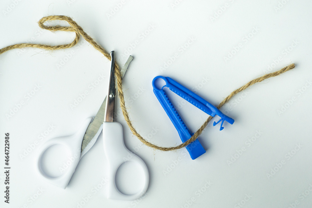 sterile scissors and umbilical cord clamp with a rope on white ...