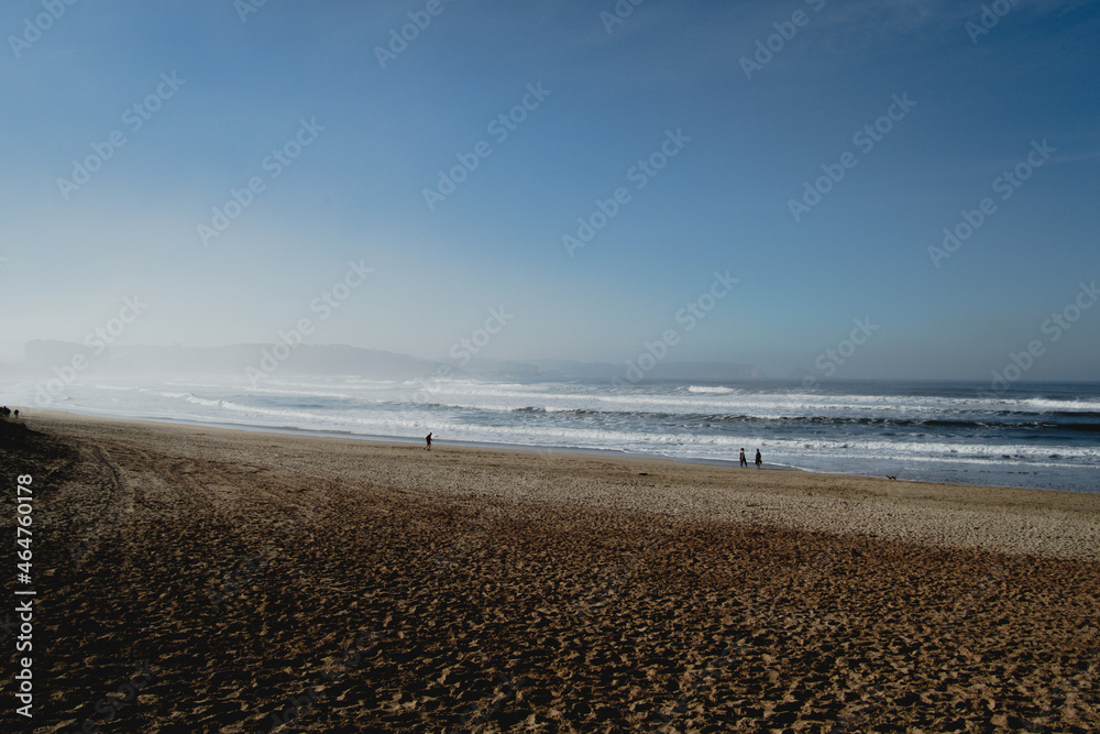 Playa en un día soleado con la bruma del mar y la niebla de fondo sobre ...