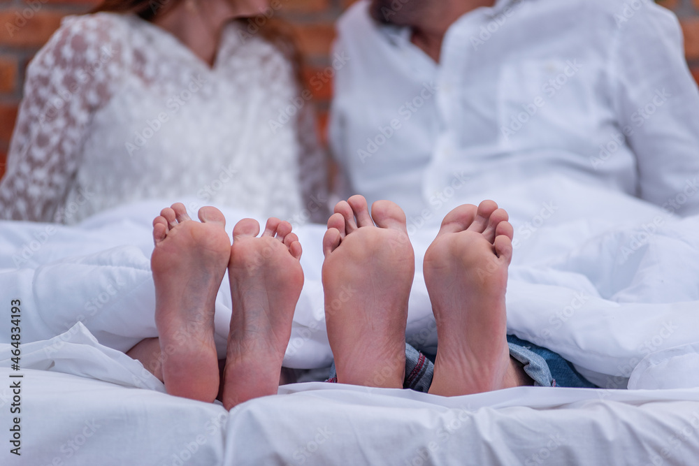 From under the white she covered two pairs of feet of couple in love ...