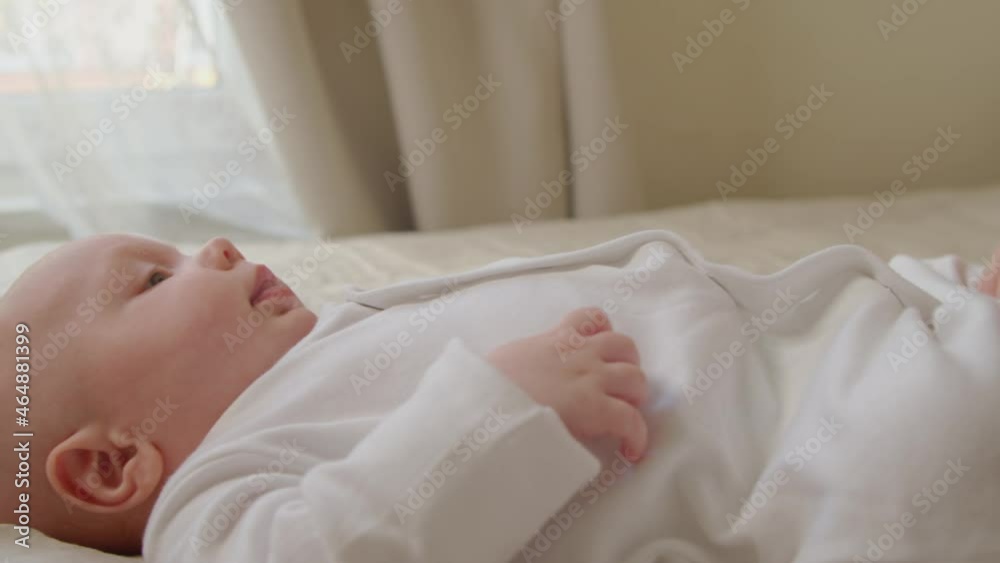 Newborn baby lying on his back in the crib mom massaging, warming up ...