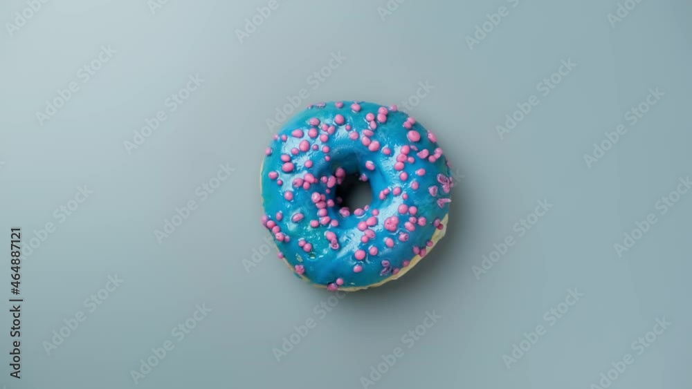 Vidéo Stock Blue frosting donut with sprinkles at light blue or gray ...