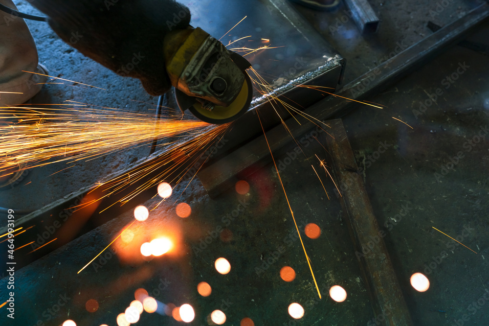 Industrial worker using angle grinder grinding metal on welding seams ...