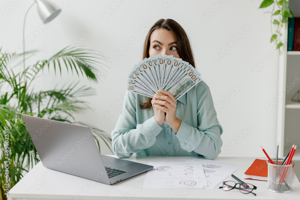Young employee business woman in blue shirt holding fan of cash money ...