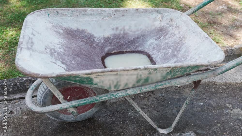 Rusty dirty industrial wheelbarrow with liquid water and cement ...