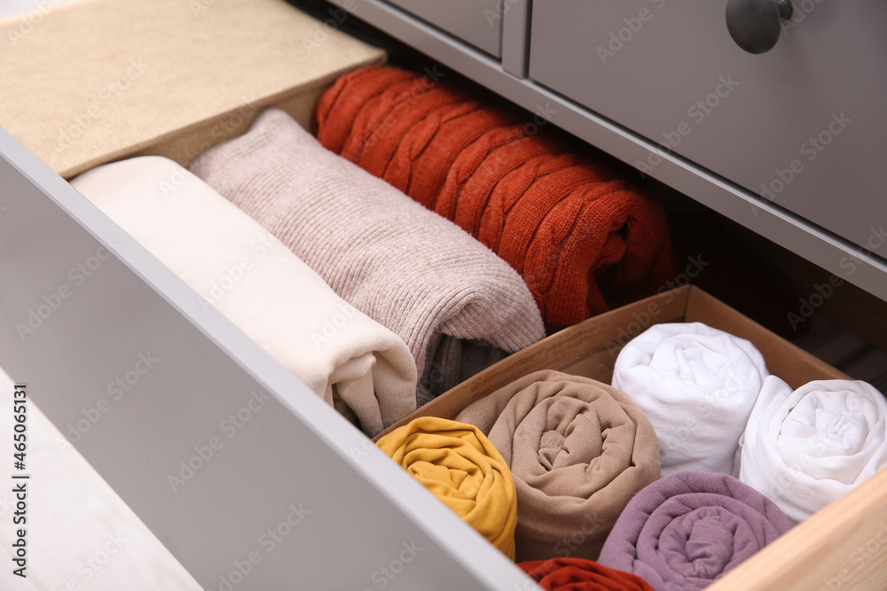 Open drawer with folded clothes indoors, closeup. Vertical storage ...