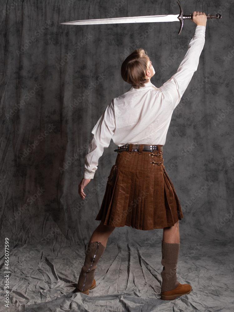 A young man in a leather kilt and a white lace-up blouse. He raised the ...