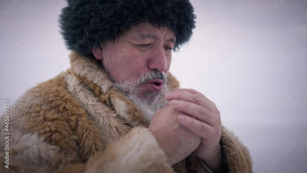 Old man blowing on hands warming outdoors on cold winter day ...