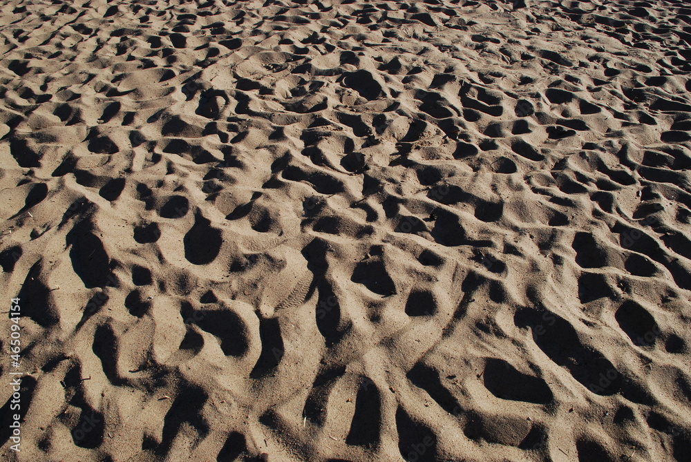 Beach sand with dents from the feet. Summer day the sun illuminates the ...