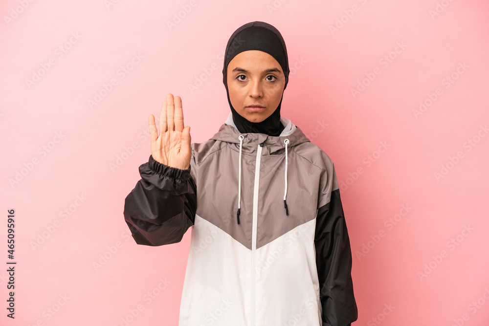 Young Arab woman with sport burqa isolated on pink background standing ...