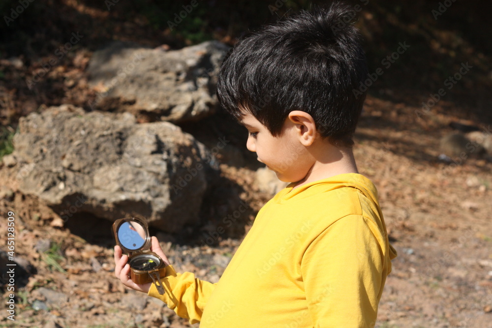 Child orienting himself with a compass on a hiking trail. the focus is ...