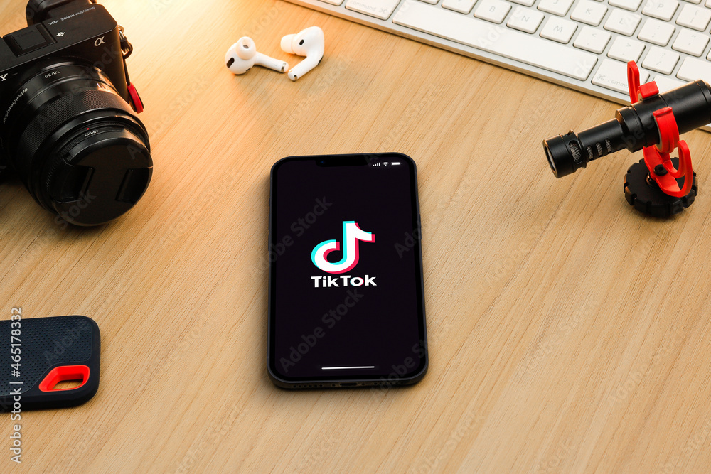 Tik Tok app on smartphone iPhone 13 Pro screen on wooden table. Content ...