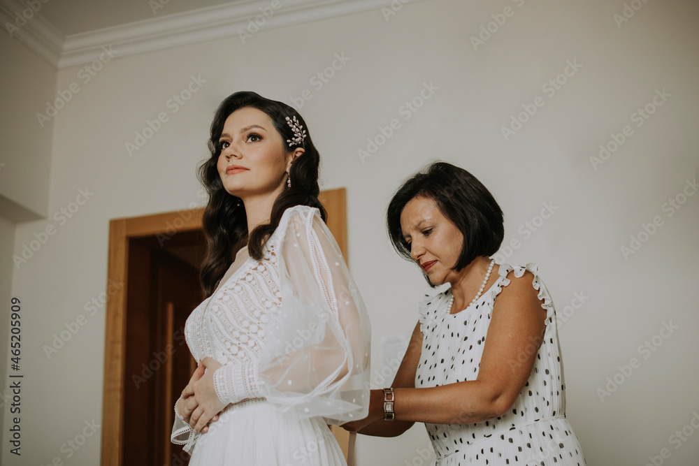 Mother helping daughter getting dressed for wedding at home Stock Photo | Adobe Stock