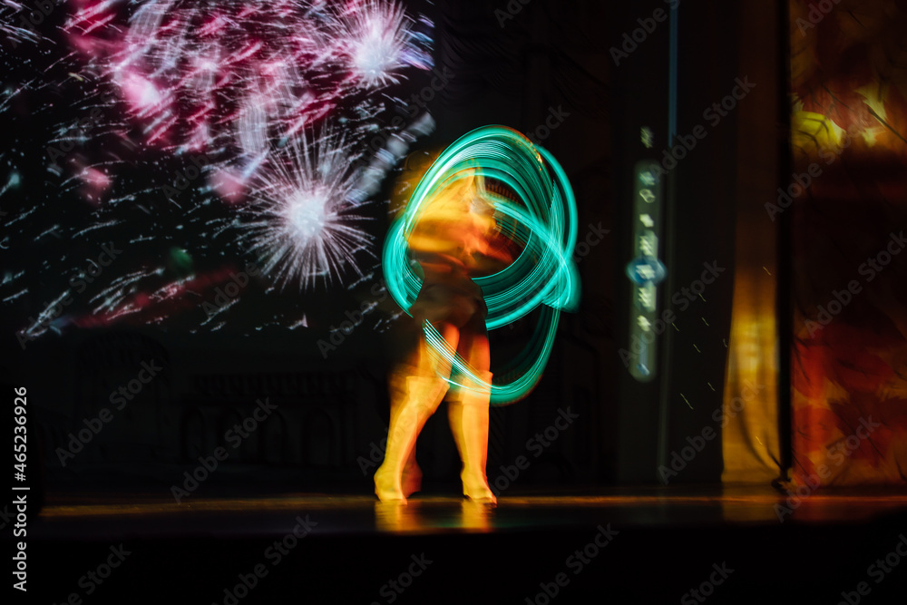 an artist on stage with glowing hoops. a girl in an LED suit performs ...