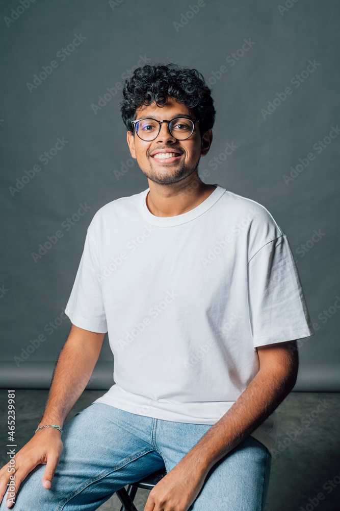 Young man sitting on chair in front of gray backdrop Stock Photo ...