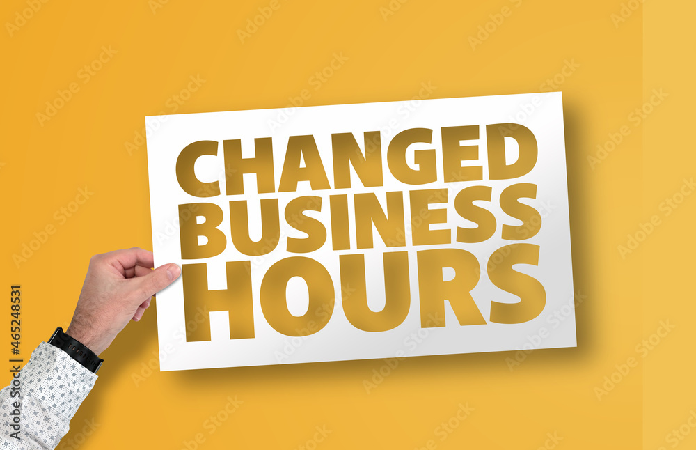 hand holding CHANGED BUSINESS HOURS sign against orange background ...