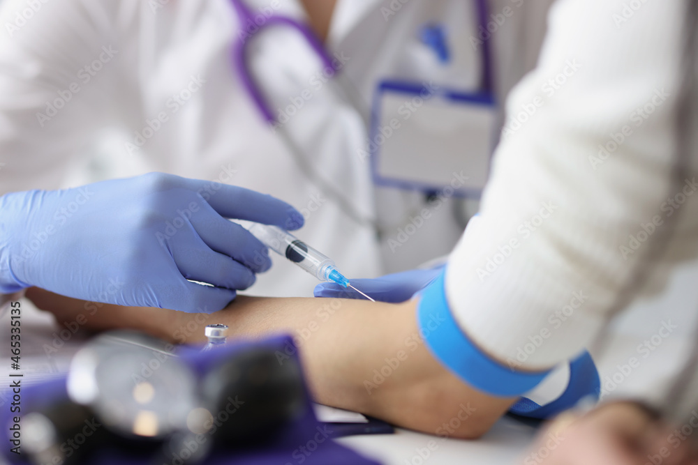 Nurse giving intravenous injection into patient ulnar vein at clinic ...