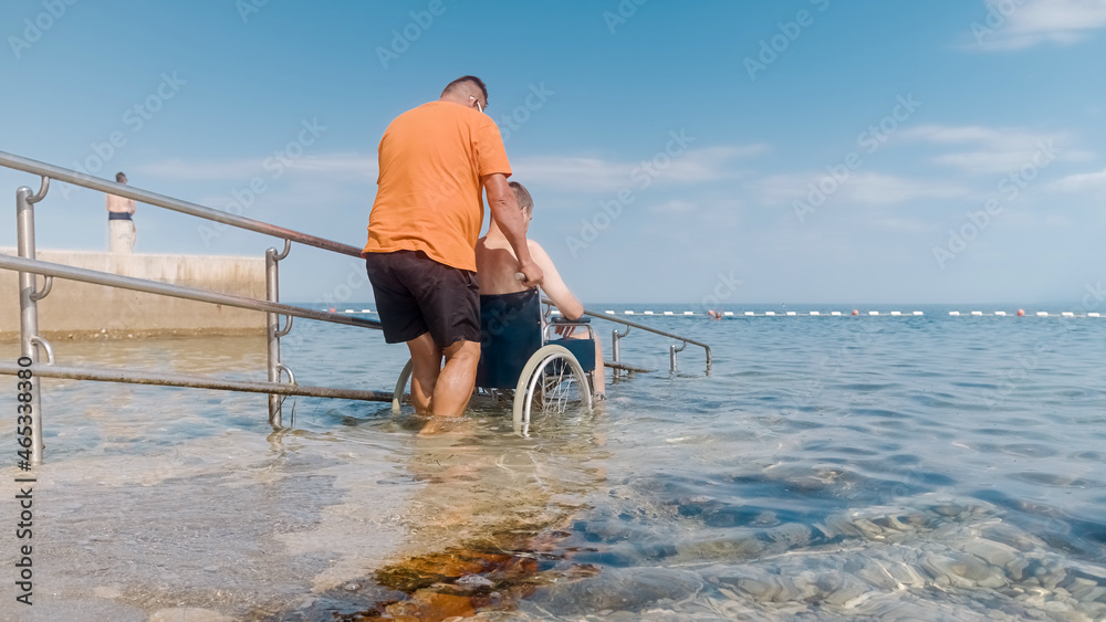 Man with disability on a wheelchair being transported into sea for ...