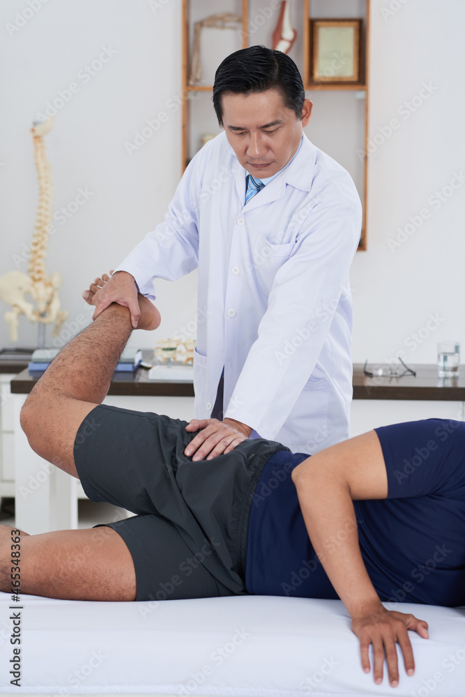 Vertical medium long shot of mature Asian physical therapist wearing ...