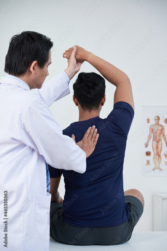 Vertical medium back view shot of modern mature osteopathic therapist ...