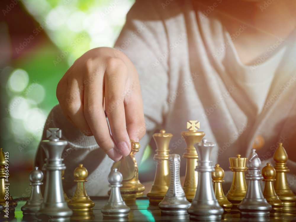 Hand businessman moving the golden knight chess fighting silver knight ...