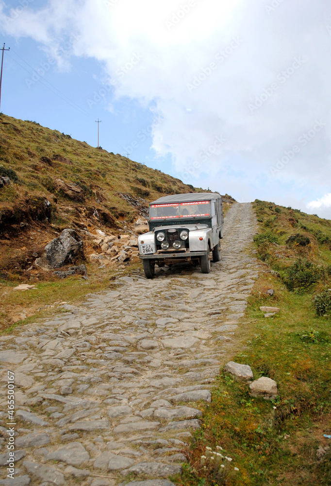 The vintage land rover plying on the graveled rough road carrying ...