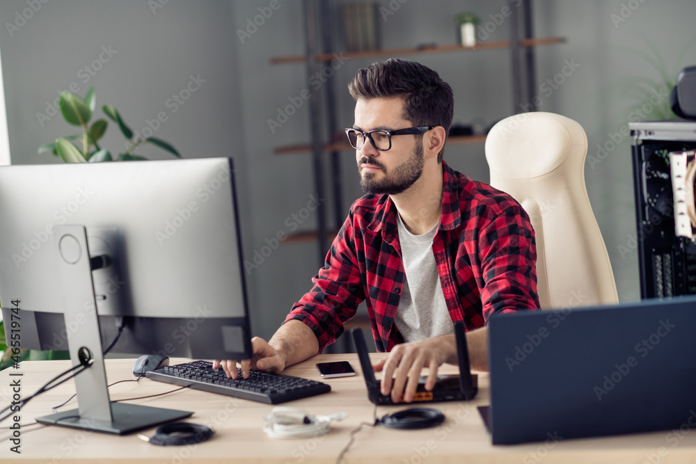Portrait of attractive skilled trendy focused guy setting wifi router ...