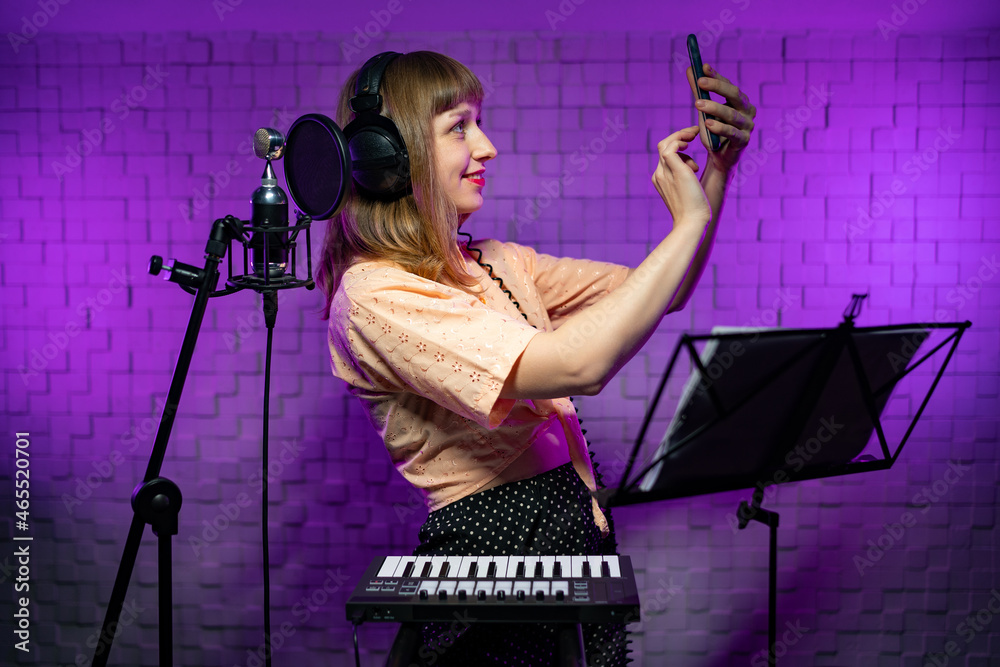 a young cute caucasian female musician in studio headphones in a room ...