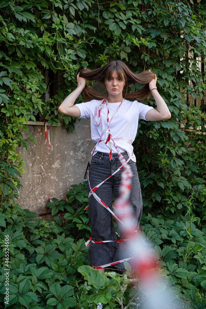 European young girl with dark hair near old wall covered with plants ...